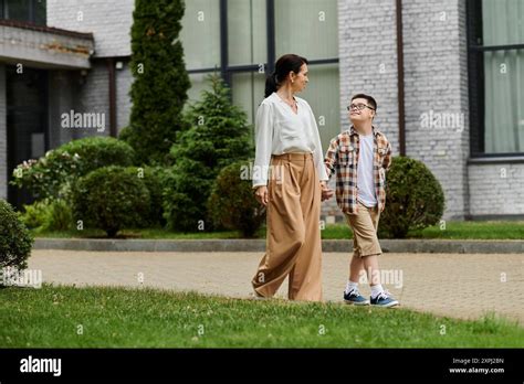 A Mother Walks Hand In Hand With Her Son Who Has Down Syndrome