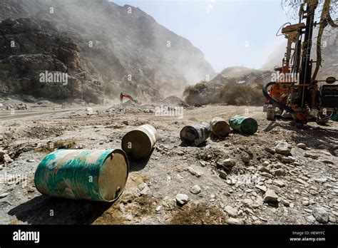 Oil Drums And Road Construction Machinery In A Dusty Desert Gorge Stock