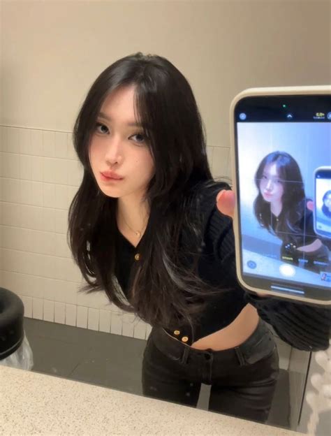 A Woman Taking A Selfie In Front Of A Mirror With Her Cell Phone Up To