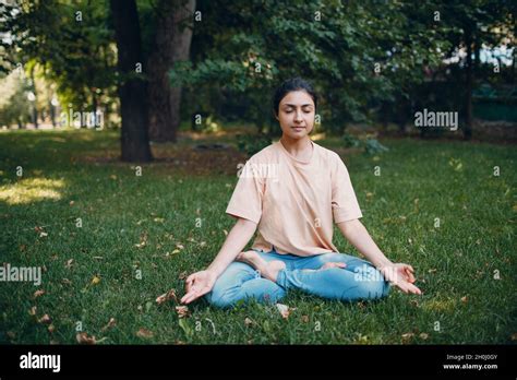 Indian Woman Doing Yoga And Meditation In Lotus Asana Pose In Outdoor Summer Park Stock Photo