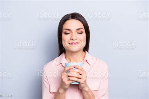 회색 배경에 고립 된 냄새를 즐기는 손에 커피 머그잔을 들고 가까운 눈과 사랑 스러운 달콤한 귀여운 멋진 예쁜 매력적인 꿈꾸는