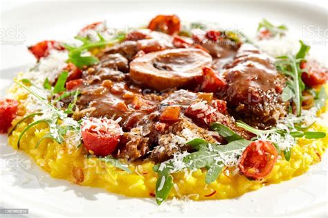 전통적인 이탈리아 요리 리조또 밀라노와 체리 토마토와 루콜라가있는 Osso Buco 흰색 배경에 고립 된 사프란 쌀이있는