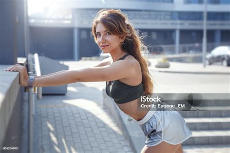 세련 된 실버에 긴 머리 스포티 한 여자 색 반바지와 어두운 녹색 T셔츠는 도시 배경에 운동 사진 중 일출에서에서 만든 아름