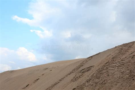 View From Below Of Large Sand Dune With No People And Sky With Clouds