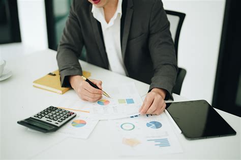 사업가 또는 회계사는 사무실에서 회계 문서를 사용하는 동안 비즈니스 데이터를 계산하기 위해 계산기와 랩톱 컴퓨터에서 작업합니다