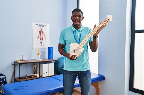 Hombre afroamericano sosteniendo un modelo anatómico de la columna