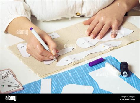 Cropped Female Seamstress Drawing Contours With Pen Of Pinned Paper
