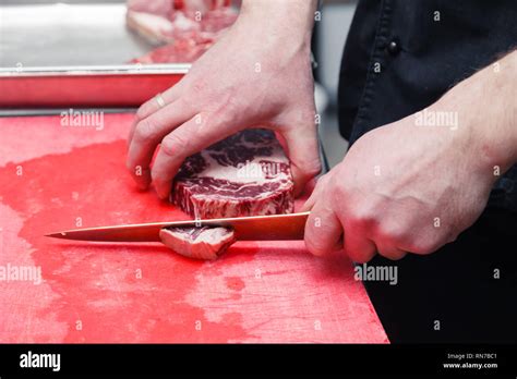 Closeup Cooks Hand Cuts Ribeye Marbled Beef Steak With Sharp Knife On