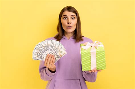 포장된 선물 상자와 돌라 지폐를 들고 입을 벌려 카메라를 바라보는 여자 25 29세에 대한 스톡 사진 및 기타 이미지 25