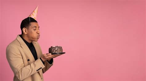 Homme Soufflant Des Bougies Sur Un Gâteau D anniversaire Photo Gratuite