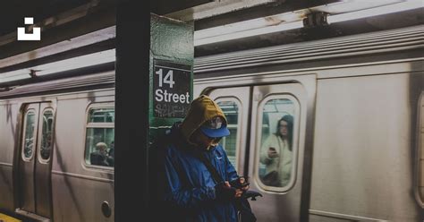 파란 까마귀를 입은 남자가 기차역에서 스마트폰을 사용하고 있다 사진 Unsplash의 무료 뉴욕 이미지