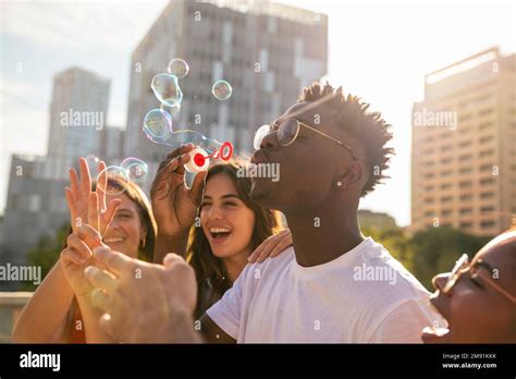 Group Of Multiracial Happy Friends Having Fun With Soap Bubbles In The