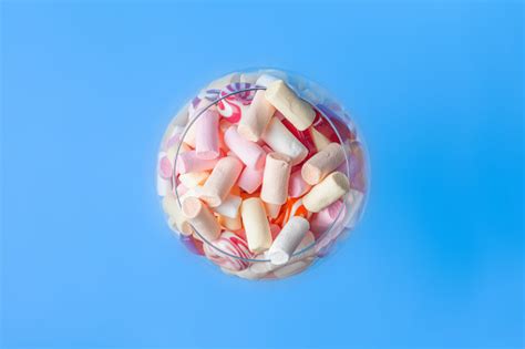 파란색 배경에 유리에 미니 마시멜로 와인 잔에 여러 가지 색상의 마시멜로 위에서 볼 수 있습니다 공간을 복사합니다 클로즈업