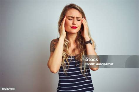 젊은 아름 다운 여자 를 입고 줄무늬 T셔츠 위에 서 흰색 고립 된 배경 에 손으로 두통 때문에 스트레스 편두통을 앓고 있습니다