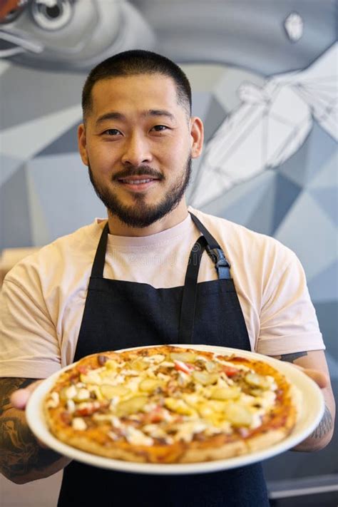Contented Cook Holding A Yummy Pizza And Looking At Camera Stock Image