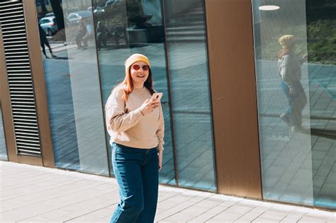 노란 모자와 분홍색 선글라스를 쓴 30대 소녀가 소셜 미디어를 확인하고 야외에서 스마트폰을 들고 있는 행복한 여성 도시 생활 개념 나그네 30 39세에 대한 스톡 사진 및