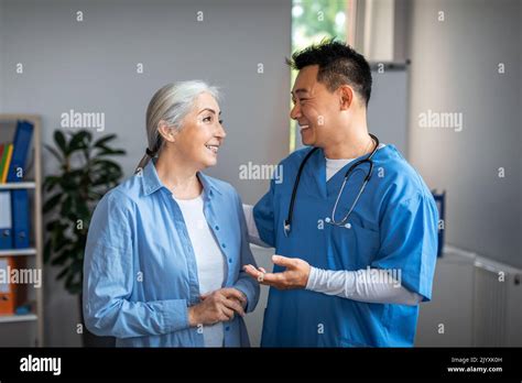 Cheerful Millennial Japanese Man Doctor Meets And Talks With Aged