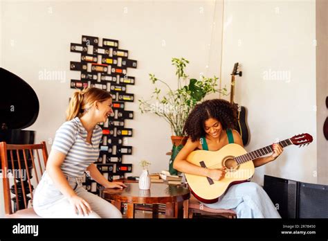 Two Laughing Multiracial Cute Girls Are Sitting In A Music Store Or A