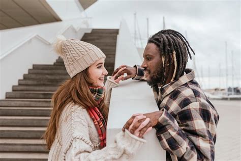 Casal jovem multirracial feliz está de mãos dadas olhando um para o