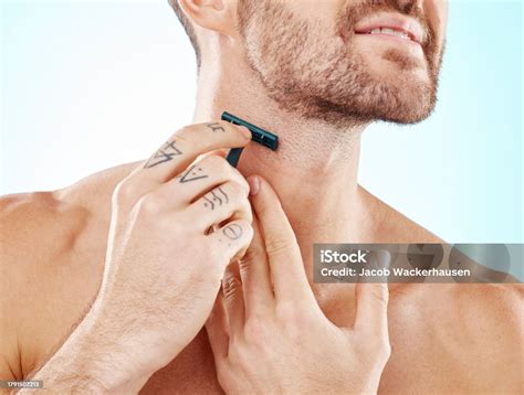 손 면도 턱수염 스킨케어 또는 위생을 위해 파란색 배경의 스튜디오에서 그루밍하는 남성 아침 일과의 일환으로 제모를 위해 욕실에서 남성과 함께 면도 문신 및 목 25 29세에