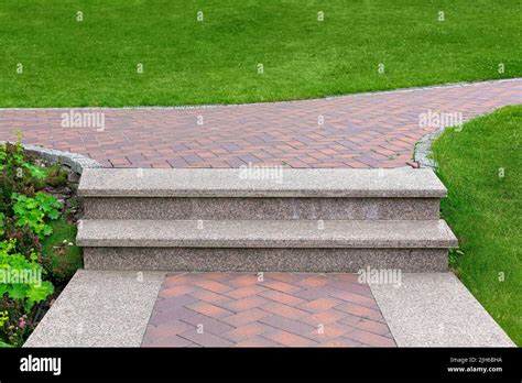 Granite Steps On A Slope Along A Pavement Of Stone Tiles Surrounded By
