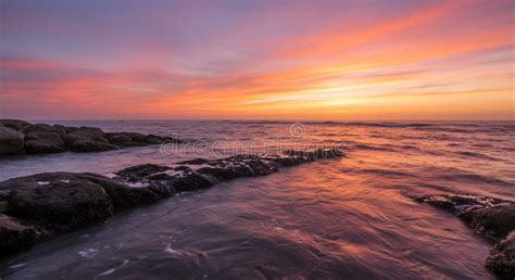 Wide Angle Landscape Of Ocean Waves Crashing Gently Against A Rocky Shoreline During A Serene