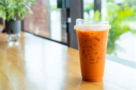 Premium Photo Iced Thai Milk Tea In A Plastic Cup On A Wooden Table