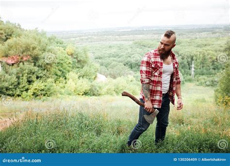 Bearded Lumberjack Worker Standing In Forest With Axe Stock Image