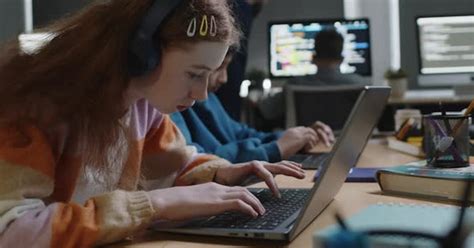 Redhead Teenage Girl Writing Computer Code On Laptop In Class