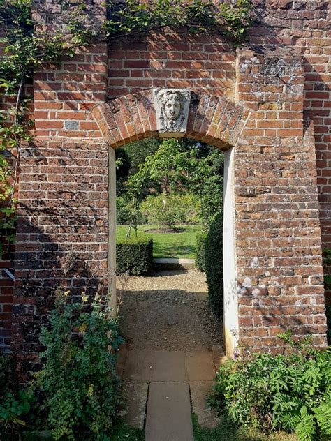 A View Through A Gateway In A Red Brick Wall To A Garden Beyond Stock