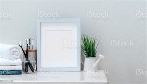 흰색 나무 꼭대기 테이블에 깨끗한 수건 칫솔 및 하우스 플랜트가있는 흰색 나무 사진 프레임을 모형으로 만듭니다 액자에 대한 스톡