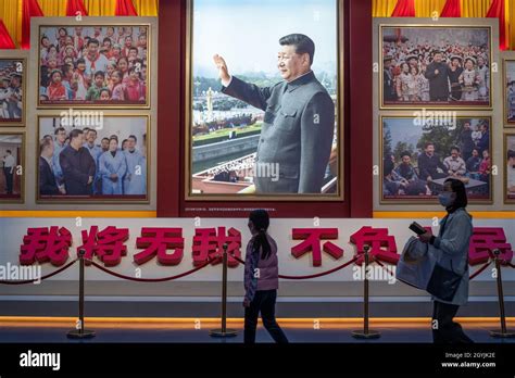 People Walk Past Images Showing Chinese President Xi Jinping At The