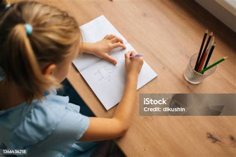 창으로 가벼운 어린이 방에 테이블에 앉아 사진을 만드는 펜으로 그림인식 할 수없는 기본 어린 소녀 그림의 높은 각도 측면 보기 가정의 방에 대한 스톡 사진 및 기타 이미지