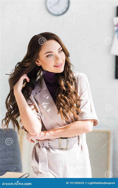 Chica Rizada Sonriendo Mientras Se Pone De Pie Y Toca El Pelo Imagen De