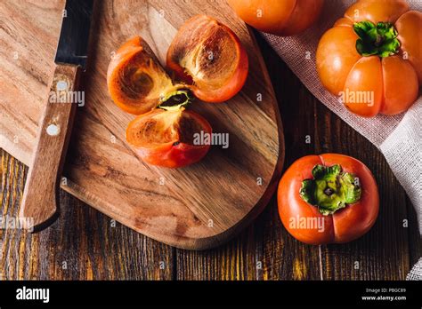 Persimmon Slices On Cutting Board With Kitchen Knife And Persimmons