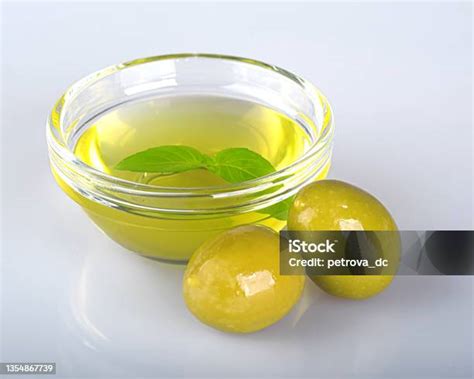 몇 가지 큰 아름다운 녹색 올리브 반사와 광택 빛 배경에 고립 된 바질의 잔가지와 유리 그릇에 올리브 오일 클로즈업 0명에 대한