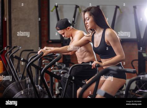 Woman And Man Biking In Gym Exercising Legs Doing Cardio Workout Cycling Bikes Stock Photo Alamy