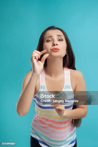 긴 머리를 가진 갈색 머리 여자 줄무늬 셔츠와 검은 레깅스를 입고 파란색 스튜디오 배경에 대해 포즈 진지한 감정 클로즈업 가공의 인물에 대한 스톡 사진 및 기타 이미지