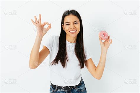 美丽开朗的年轻女子拿着甜甜圈