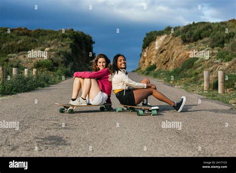 Full Body Side View Of Cheerful Multiethnic Girlfriends Sitting On
