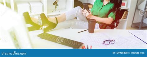 A Young Girl Sits In The Office Threw Her Legs On The Table And Holds