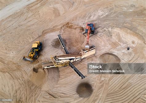 重い鉱山機械と砂の露天掘りのarialビューオープンピット鉱山の移動式石の顎のクラッシャー機械オープンキャストでホイールローダーとダンプ