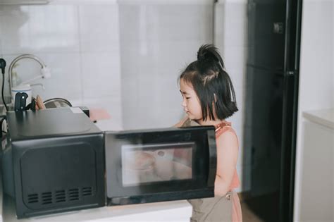 젊은 아시아 중국 여자 점점 그녀의 음식 아웃 부터 전자 레인지 사용 보호 장갑 에 부엌 전자레인지에 대한 스톡 사진 및 기타