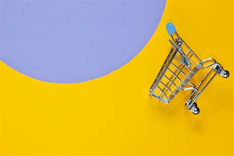 기하학적 모양의 컬러 종이 배경에 쇼핑 트롤리 쇼핑 중독 개념입니다 팝 아트 스타일입니다 공간을 복사합니다 맨 위 보기 개념에