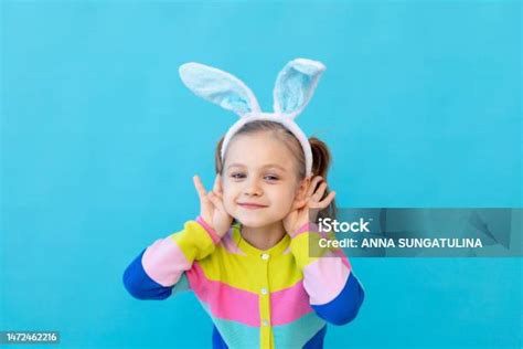 줄무늬 재킷에 토끼 귀를 가진 어린 소녀의 초상화미소와 탐닉 부활절 휴일의 개념 파란색 배경 사진 스튜디오 텍스트 장소 6 7