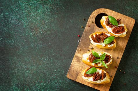 와인에 대 한 이탈리아 전채 간식입니다 부드러운 치즈와 말린 토마토 Brushetta 돌 테이블에 소박한 나무 보드에 제공