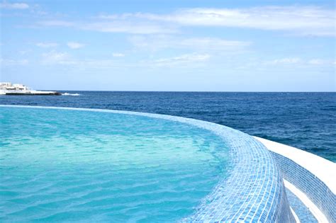 海の景色を望むリゾートのスイミングプールの青い澄んだ水面夏休みと休息のコンセプト豪華なビーチヴィラハウス青いタイルのモザイクパターン
