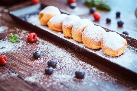 Donuts Sprinkled With Powdered Sugar On A Black Long Plate With