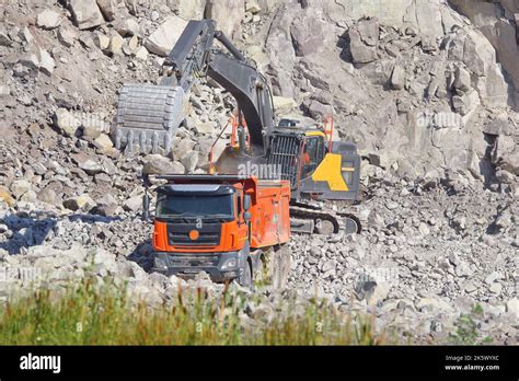 The Yellow Hydraulic Crawler Excavator Loading Stones Into An Orange