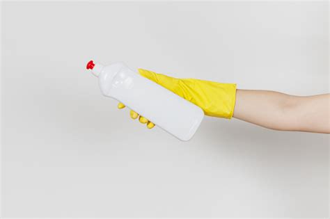 텍스트 흰색 배경에서 고립 된 장소 설거지 청소 액체와 노란색 장갑 보유 흰색 병에 여성 손의 닫습니다 청소 공급 개념입니다